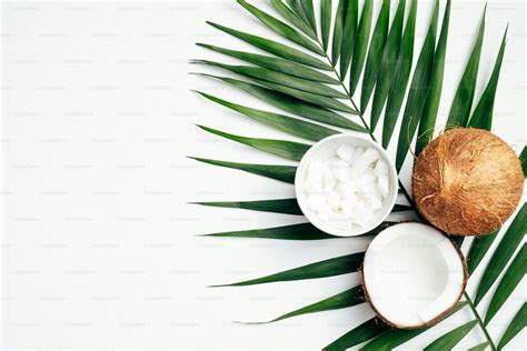 반쪽과 코코넛 플레이크가 그릇에 뿌려진 코코넛 과일 흰색 바탕에 열대 야자 잎 플랫 레이 평면도 여름 배경입니다 사진 Unsplash의 건강한 라이프스타일 이미지