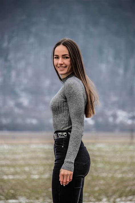 A Woman In Gray Long Sleeves Shirt And Black Denim Jeans Standing On