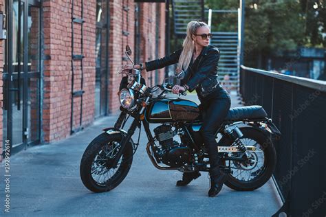 Female Biker In Full Leather Suit Is Posing For Photographer While