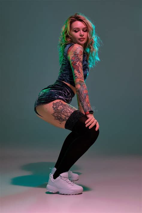 Blond Woman With Tattoed Body And Long Curly Hair Is Dancing Twerk In