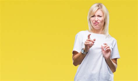 격리 된 배경 위에 흰색 T셔츠를 입고 젊은 아름 다운 금발의 여 자가 혐오 식 불쾌 하 고 두려워 하기 때문에 역 겨 운 얼굴을 하 고 혐오 반응 손으로 발생합니다 성가신