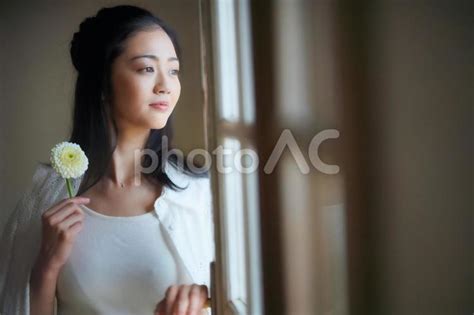 白いお花を持って遠くを見る女性 No 24275692｜写真素材なら「写真ac」無料（フリー）ダウンロードok