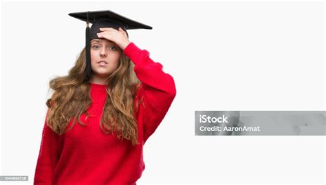 젊은 금발 여 자가 머리에 손으로 압박 하는 졸업 모자를 쓰고 충격 수치심과 깜짝 얼굴로 분노와 좌절 두려워 하 고 실수에 대 한 화가 감정에 대한 스톡 사진 및 기타