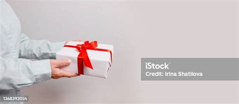 분홍색 파스텔 배경에 빨간 새틴 활이 있는 깜짝 선물 패키지 박스를 들고 있는 여성의 손을 클로즈업하여 복사 공간을 촬영합니다 발렌타인 선물 계절에 대한 스톡 사진 및 기타