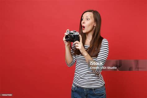 젊은 여 자가 입 벌리고 유지 하는 복고풍 빈티지 사진 카메라 들고 놀 밝은 빨간 벽 바탕에 고립 된 보고 놀 랐 다 사람들이