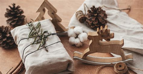 소나무 콘 나무 순록 꼬기 면이 있는 나무 테이블에 녹색 가지가 있는 린넨 패브릭으로 싸인 세련된 크리스마스 소박한 선물 심플한 에코는 플라스틱을 무료로 선물합니다