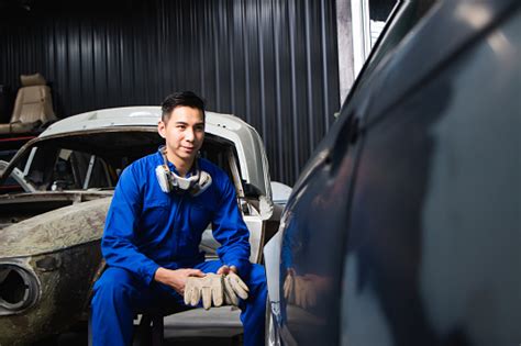 기업가 사업가 중소기업 소유자 차고 자동차 수리점 화가 점프 수트와 먼지 마스크를 착용 차고에 앉아 휴대 전화와 노트북을 사용합니다 아시아인에 대한 스톡 사진 및 기타