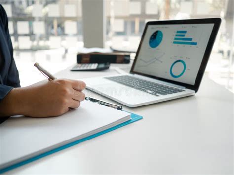 Business Woman Working At A Computer Writing A Note In Chart Finance