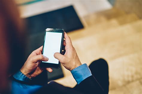 온라인 예약 및 뱅킹을위한 인터넷 광고를위한 복사 공간 영역이있는 모형 휴대 전화 가젯을 사용하는 남성 사업가의 자른 이미지 빈 화면이있는 스마트 폰 장치에 선택적 초점