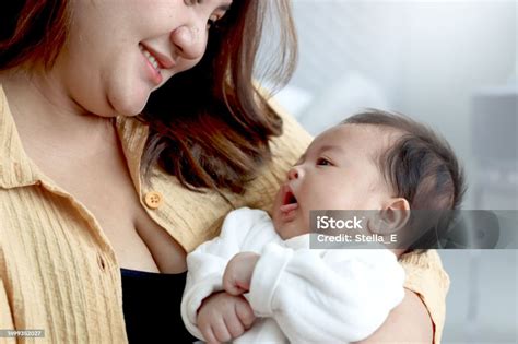 어머니는 갓 태어난 아기를 팔에 안고 침실의 침대에서 그와 함께 놀고 사랑스러운 가족 엄마와 아이가 함께 시간을 보내고 부모는 아이를 돌보고 출산 후 뚱뚱한 몸매를 가진