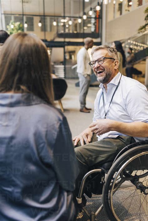 Happy Male Entrepreneur With Disability Sitting On Wheelchair During Networking Event At