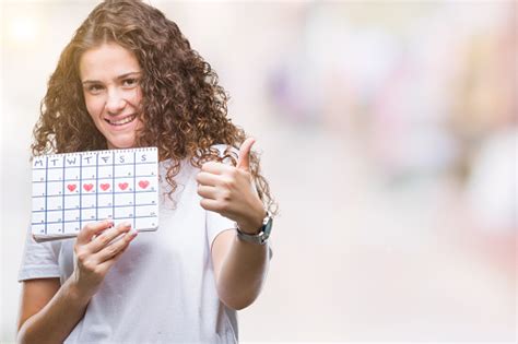 고립 된 배경 위에 생리 달력을 들고 젊은 갈색 머리 소녀 확인 기호를 수행 하는 큰 미소로 행복 손가락으로 엄지손가락 우수한 기호 소녀에 대한 스톡 사진 및 기타 이미지