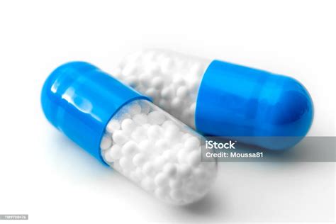 제약 산업 통증 관리 약물 및 매크로와 약물 개념 테마 밝은 흰색 배경에 고립 된 마이크로 과립으로 채워진 두 개의 파란색투명 알약에 클로즈업 0명에 대한 스톡 사진 및