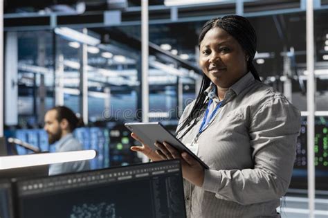 Portrait Of Smiling Data Center Programmer Using Tablet To Update Servers Tech Stock Image