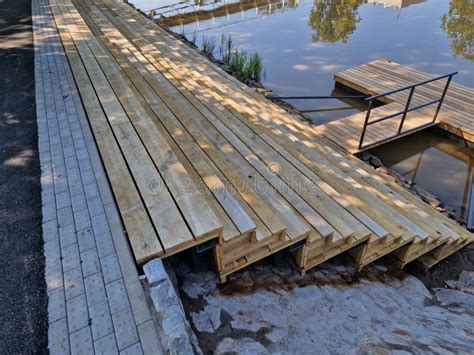A Floating Jetty For Mooring Ships Is Fixed With Metal Rods On Hinges Wooden Stairs Are Benches