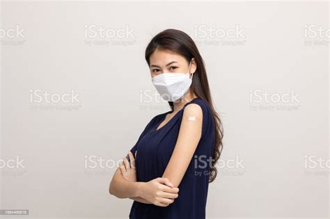 젊은 아름다운 아시아 여성은 마스크를 착용하고 코로나 바이러스를 보호하는 백신을 받고 있습니다 고립 된 흰색 배경에 예방 접종을