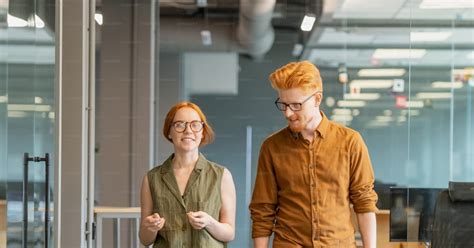 캐주얼웨어를 입은 행복한 젊은 사업가와 그녀의 잘생긴 동료가 책상을 따라 통로를 걸어 내려가 일에 대해 논의하고 있다 사진 Unsplash의 비즈니스 사람 이미지