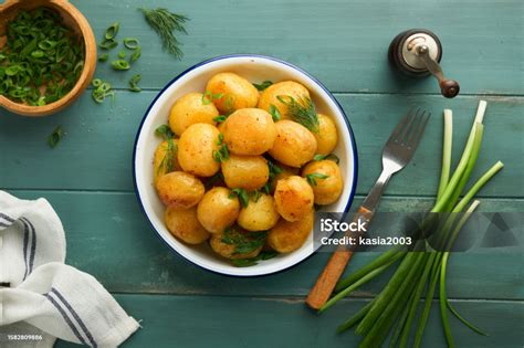 오래된 소박한 나무 배경에 하얀 그릇에 버터 신선한 딜 양파를 곁들인 신선한 삶은 새 감자 또는 어린 감자 맛있는 새 삶은 감자