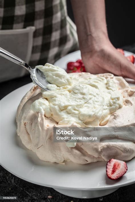 신선한 딸기와 휘핑 크림을 곁들인 맛있는 수제 파블로바 케이크 맛있는 머랭 케이크 수직 이미지를 장식하는 여성 제빵사 평면도