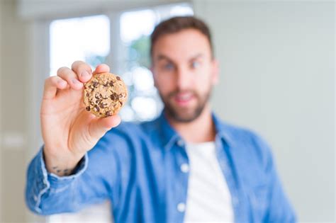 초콜릿 칩 쿠키를 먹는 잘생긴 남자는 깜짝 얼굴이 충격에 무서 워 두려워 하 고 공포 표현으로 흥분 감정에 대한 스톡 사진 및 기타 이미지 Istock