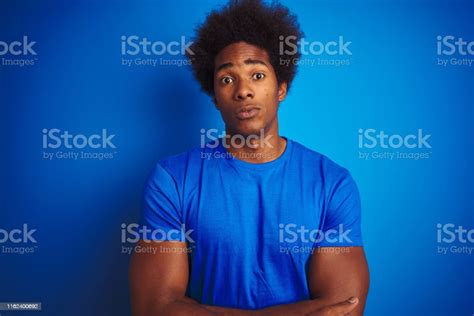 고립된 파란색 배경 에 서 티셔츠를 입고 아프리카 계 미국인 남자 회의적이고 긴장 교차 팔로 얼굴에 표정을 거부 부정적인 사람