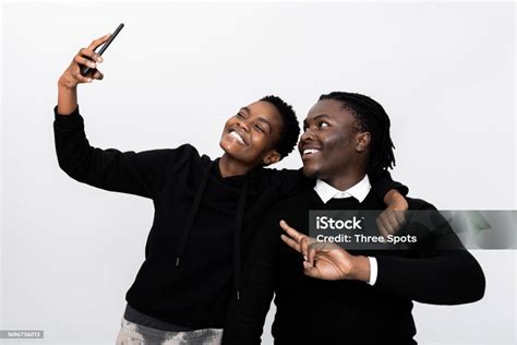 검은 옷을 입은 예쁜 흑인 아프리카계 미국인 커플 남자와 여자가 전화로 화상 회의를 하고 있는 동안 스튜디오에서 격리된 촬영 과정을 진행하는 동안 가족 친구들에게 전화를