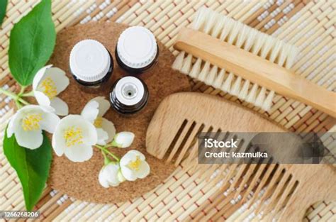 필수 재스민 오일 나무 머리와 바디 브러시와 재스민 꽃을 가진 세 개의 작은 유리 병 아로마테라피 스파 한방 의학 성분 상단