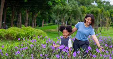 공원에서 행복한 혼혈 가족 어린 딸과 함께 손을 잡고 정원을 함께 걷고 있는 어머니 엄마와 아이 여자 아이는 여름 야외 활동 주말 휴가에서 즐기고 재미있게 놀고 있습니다