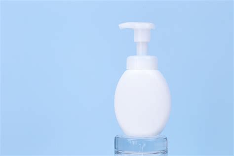 유리 연단에 펌프가있는 흰색 병과 파란색 배경에 큰 흰색 타조 깃털 선스크린 브랜딩을 위한 빈 라벨 병 화장품 포장 모형 0명에 대한 스톡 사진 및 기타 이미지 Istock