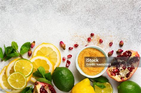 상쾌한 음료 레모네이드 모히토 또는 차가운 상쾌한 차를 위한 요리 배경 신선한 레몬 라임 석류 말린 차 장미 꽃 차 지팡이 설탕 회색 배경에 민트 꽃다발을 남깁니다 감귤류