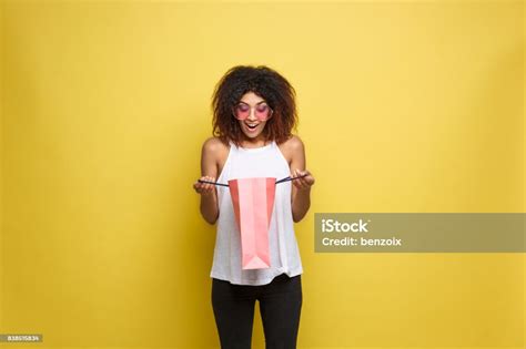 쇼핑 개념세로 젊은 아름 다운 매력적인 아프리카 여자 다채로운 쇼핑 가방 놀라운 닫습니다 옐로우 파스텔 벽 배경입니다 공간에