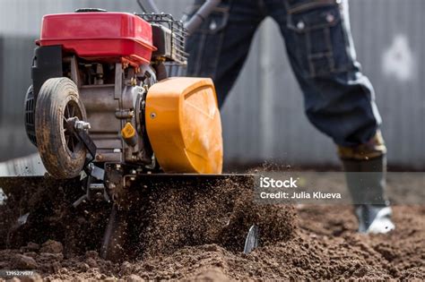 기치 한 남자 농부가 경작자와 함께 땅을 쟁기질합니다 정원에서 경작을위한 농업 기계는 수확기를 결합합니다 가루로 빻은에 대한 스톡 사진 및 기타 이미지 Istock