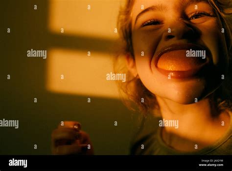 Face Of A Young Girl Sucking And Smiling With An Orange Slice In Her
