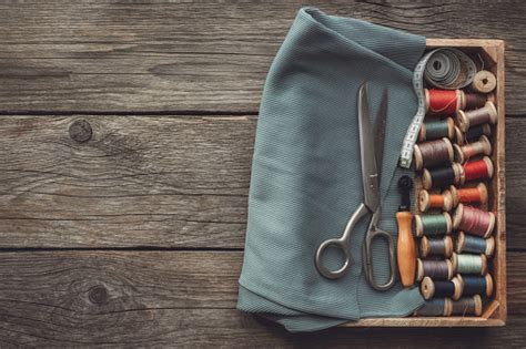 바느질 항목 복고풍 재단 가위 측정 테이프 실의 나무 스풀 나무 상자에 칼과 녹색 천을 절단 맨 위 보기 텍스트의 공간을