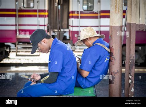 Two Railway Workers In Blue Uniforms Taking A Break On A Platform At Hua Lamphong Railway