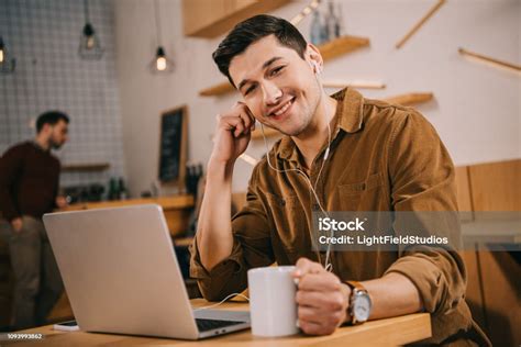 커피 한잔 들고와 카페에서 카메라를 보고 이어폰에 잘생긴 남자 갈색 머리에 대한 스톡 사진 및 기타 이미지 갈색 머리 개인 장식품 남성 Istock