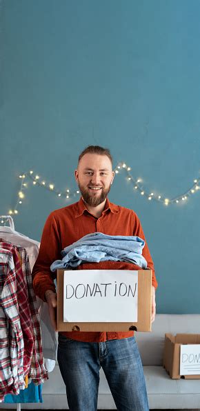 가난하고 궁핍한 사람들을 위해 낡은 헌 옷으로 가득 찬 기부 상자를 들고 웃는 남자 기부 및 자선 개념 35 39세에 대한 스톡