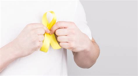 자살 육종 뼈암 방광암 간암 및 유년기 암 개념에 대한 노란 리본 인식 기호를 들고 흰색 티셔츠를 입은 젊은 남자 의료 9월에