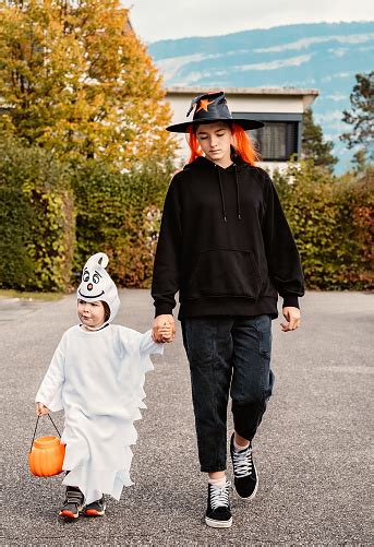 할로윈 파티를 축하하는 사탕을 수집 호박 가방과 함께 거리에서 걷고 유령 의상과 마녀 모자를 입은 아이들 형제자매는 전통적인 휴가를 축하합니다 과자 안 주면 장난칠 거예요