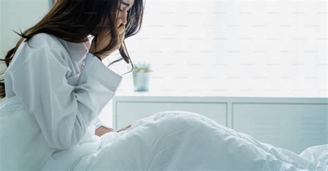 잠옷을 입은 아시아의 아름다운 아픈 소녀가 침실에서 잠에서 깨어납니다 매력적인 젊은 여성은 침대에서 일어나 이른 아침에 집에서 기침을 한 후 기분이 좋지 않습니다 건강