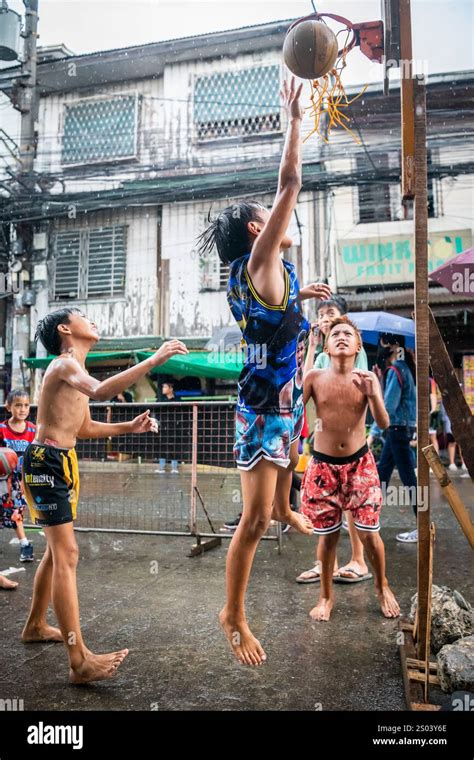 Young Filipino Boys Play Basketball During A Rain Storm On Asuncion St