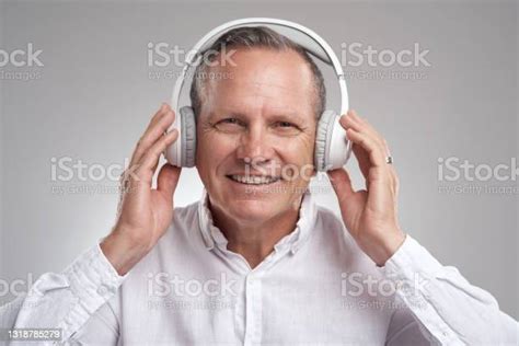 스튜디오에서 회색 배경에 서서 헤드폰을 통해 음악을 듣고 잘 생긴 성숙한 사업가의 샷 50 59세에 대한 스톡 사진 및 기타 이미지 50 59세 55 59세 개념