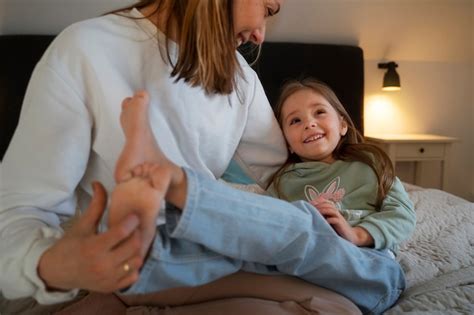 Young Mother Making Her Daughter Laugh By Tickling Her Free Photo