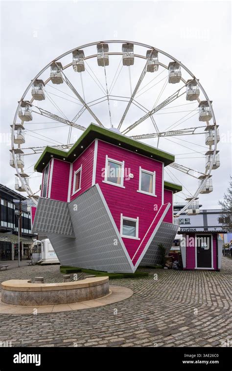 Magenta Upside Down House With A Ferris Wheel In The Background Both