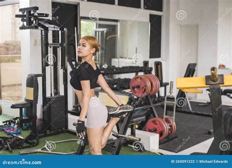 A Shapely Asian Woman Doing A Standing Quad Stretch Warming Up Before
