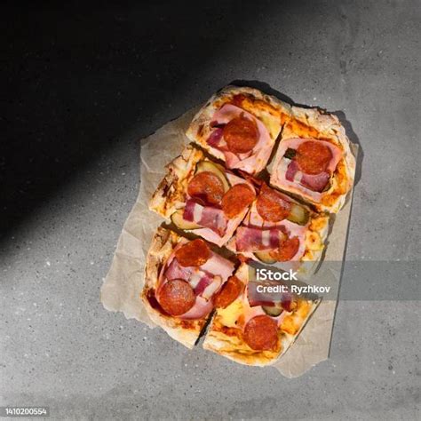 어두운 배경에 페퍼로니와 베이컨을 곁들인 전통적인 이탈리아 고기 피자 단단한 그림자가있는 회색 돌 테이블에 고기 핀사 콘크리트 배경에 페퍼로니와 베이컨이있는 로마 피자 핀사