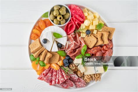 하얀 나무 배경에 다양한 치즈 살라미 쵸 리조 프로슈토 꿀 포도 견과류 올리브 빵 블루 베리 및 신선한 허브가있는 Charcuterie 보드 축제 간식 샤퀴트리에 대한 스톡