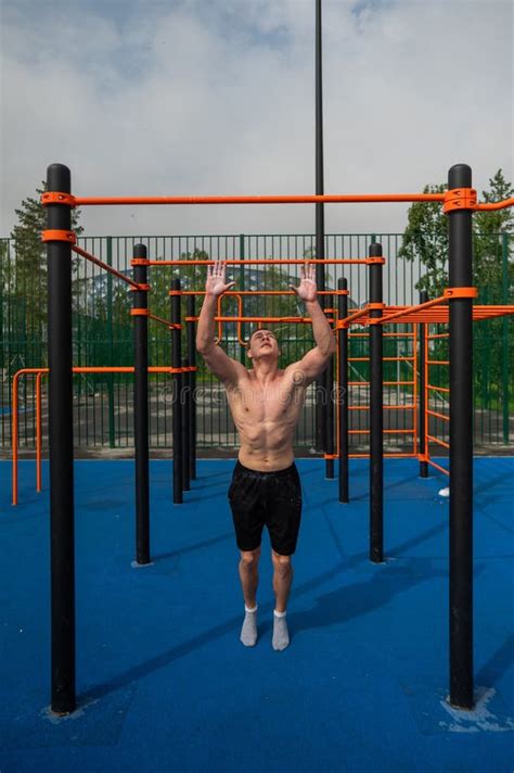 A Shirtless Man Is Doing A Workout On The Horizontal Bars Outdoors Vertical Photo Stock Image