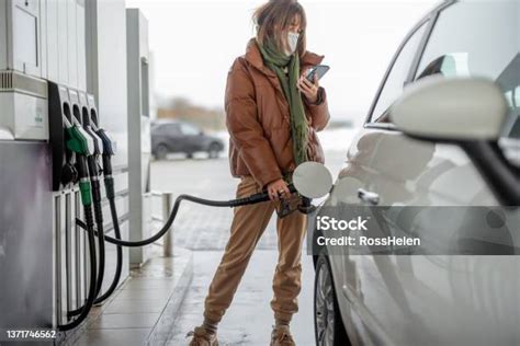 스마트 폰을 사용하여 가솔린으로 자동차를 급유하는 얼굴 마스크의 여성 주유소에 대한 스톡 사진 및 기타 이미지 주유소 펌프 정장용 구두 가솔린 Istock