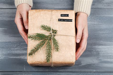 파란색 나무 배경에 나무 가지와 크래프트 에코 선물 상자를 들고 여자의 손 최고 보기 휴일 선물 개념 개념에 대한 스톡 사진 및